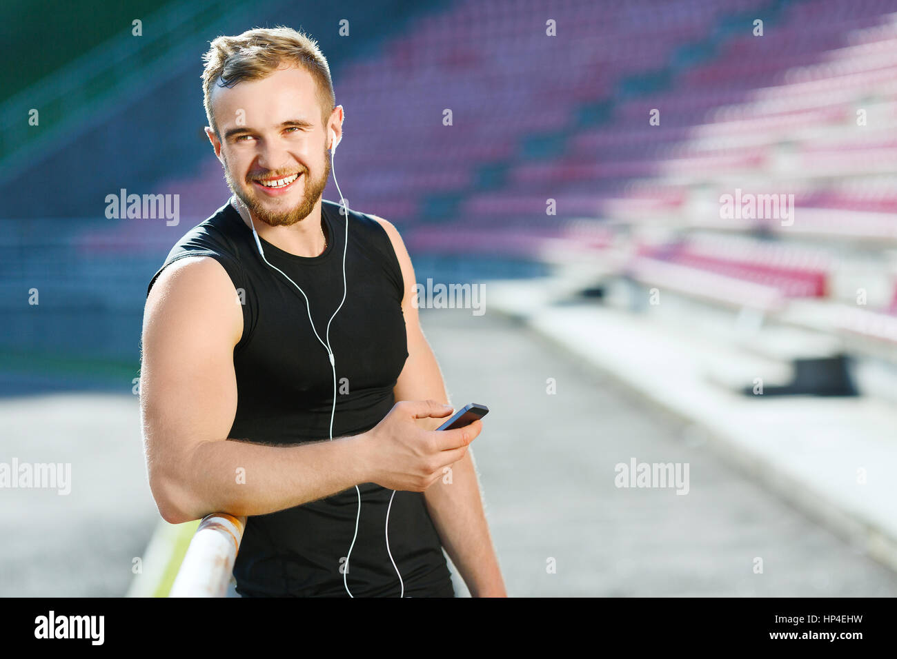 Smiling sportsman standing near tribune of stadium Stock Photo - Alamy