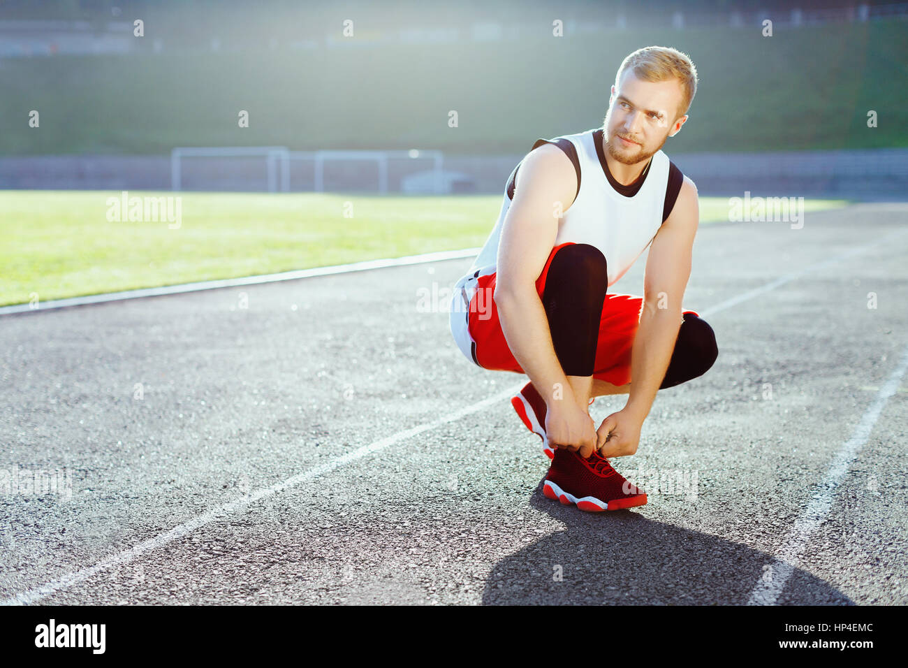 Sportsman crouched in red sneakers Stock Photo - Alamy