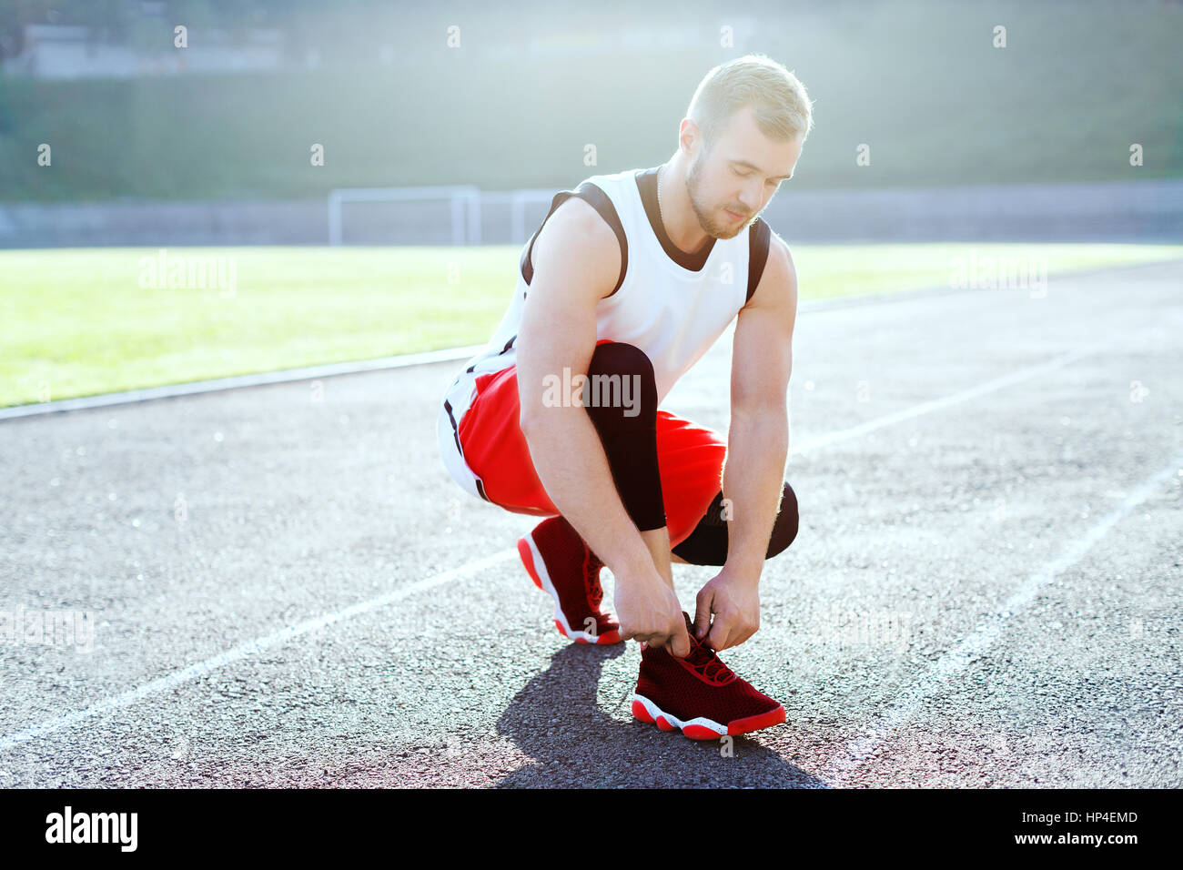 Profile of man crouched in red sneakers Stock Photo - Alamy