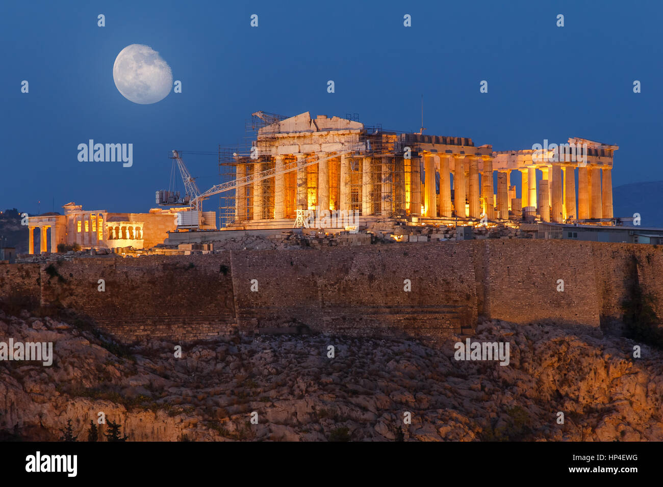 The Parthenon in Acropolis Hill in Athens, Greece shot in blue hour with the moon rising above ...