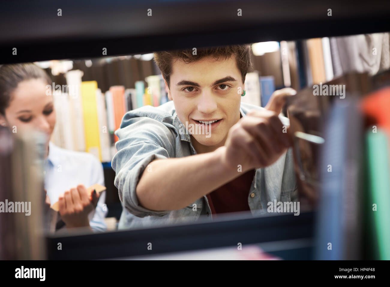 Smiling young students searching for books at the library Stock Photo ...