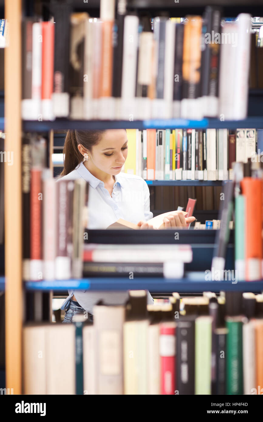Young smiling student at the library searching for books Stock Photo ...