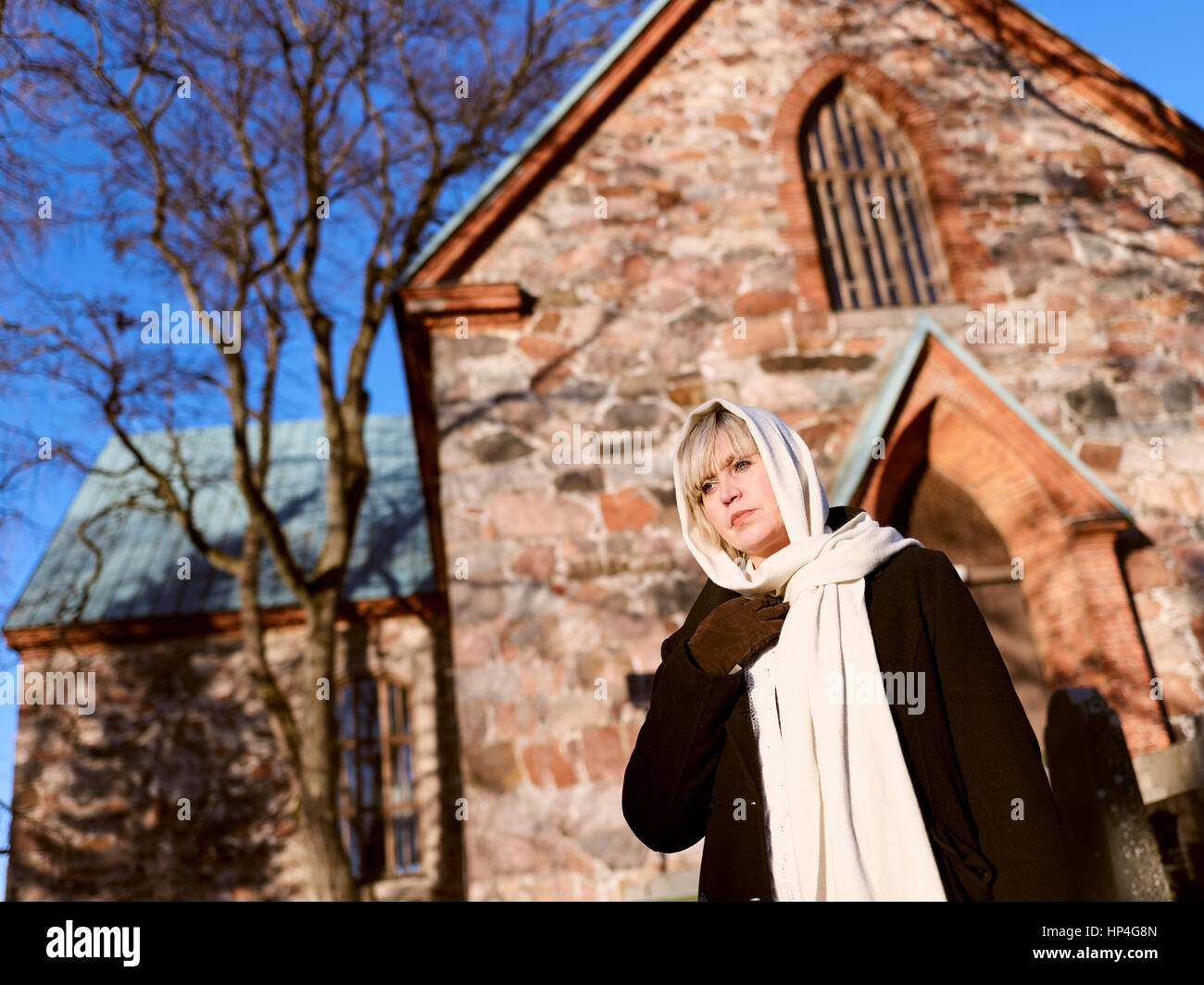 Sad mature woman, old church on background, sunny winter day Stock ...