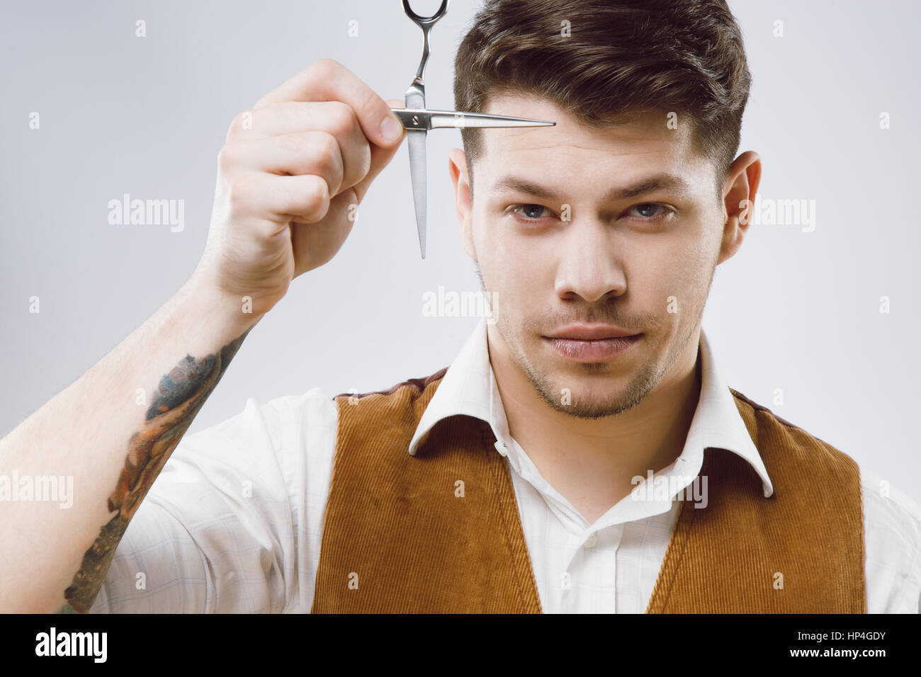 Handsome barber at gray background Stock Photo - Alamy