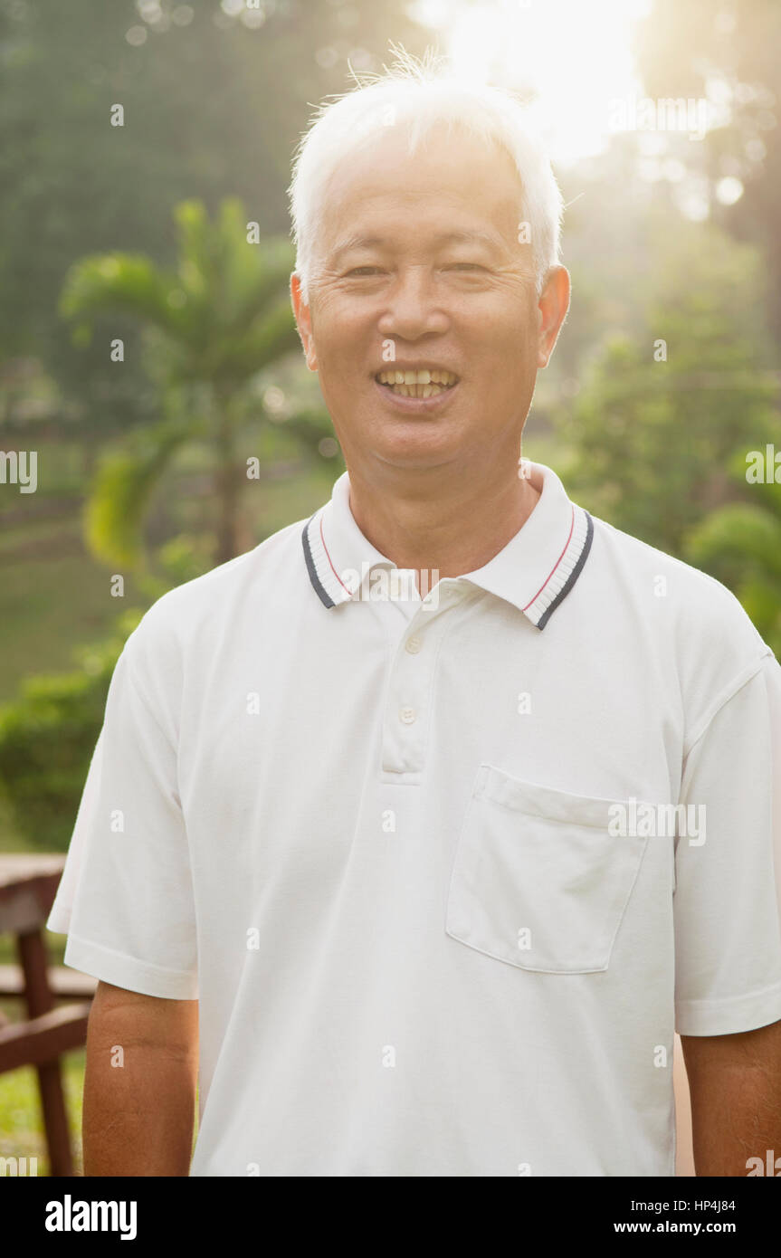 Portrait of healthy Asian senior man smiling at outdoor nature park, morning beautiful sunlight ...