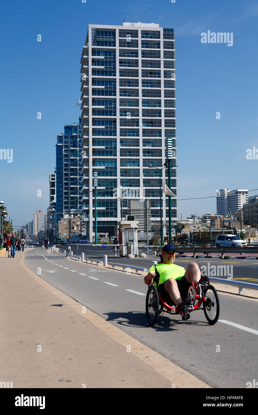 middle aged man riding recumbent bicycle on sidewalk near to beachfront ...