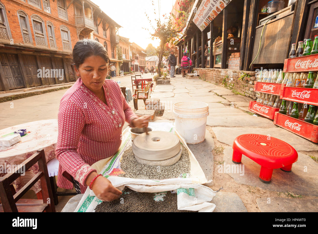 Newari woman grinding dal (dried, split pulses) with a hand-operated ...