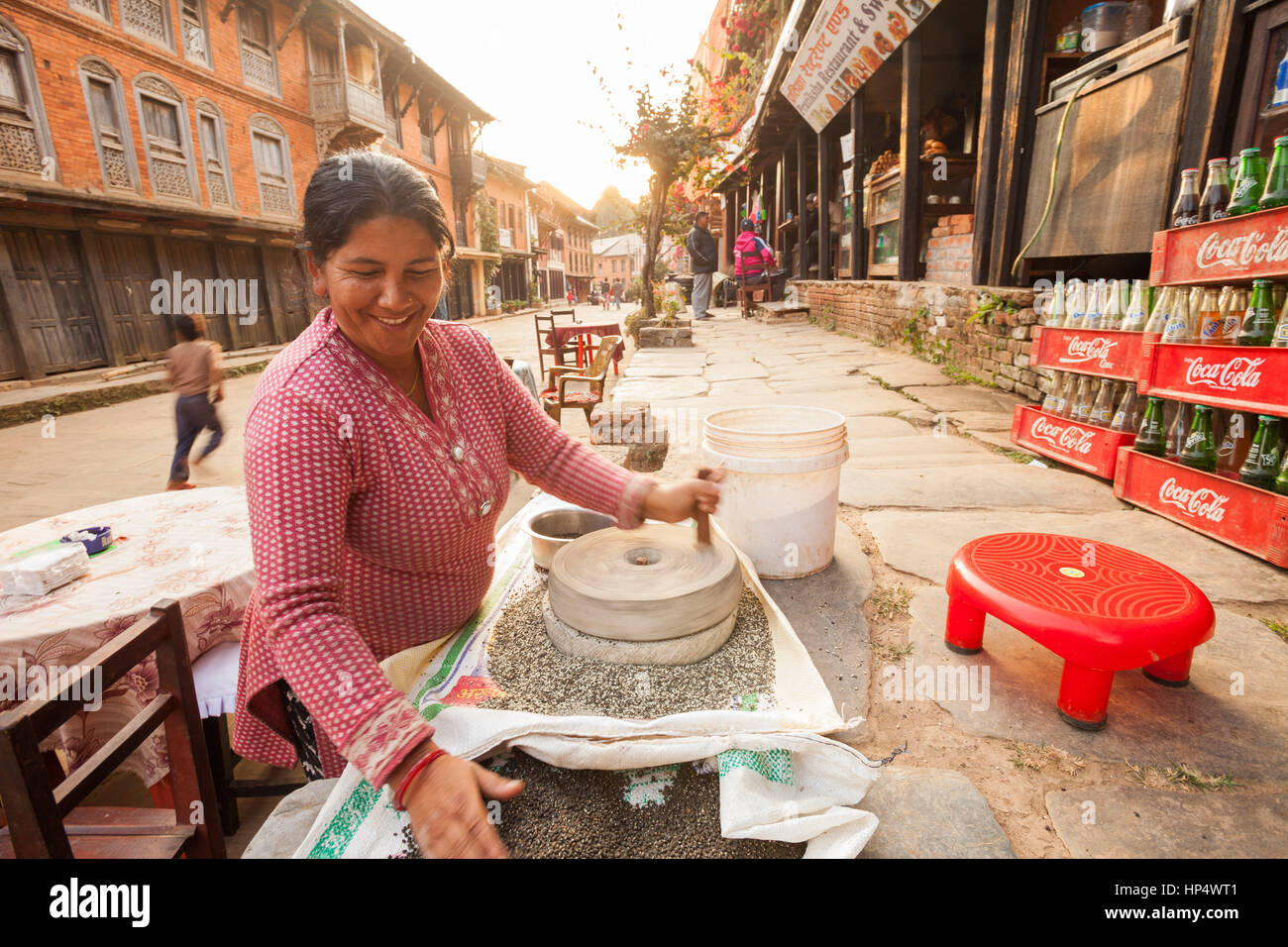 Newari woman grinding dal (dried, split pulses) with a hand-operated ...