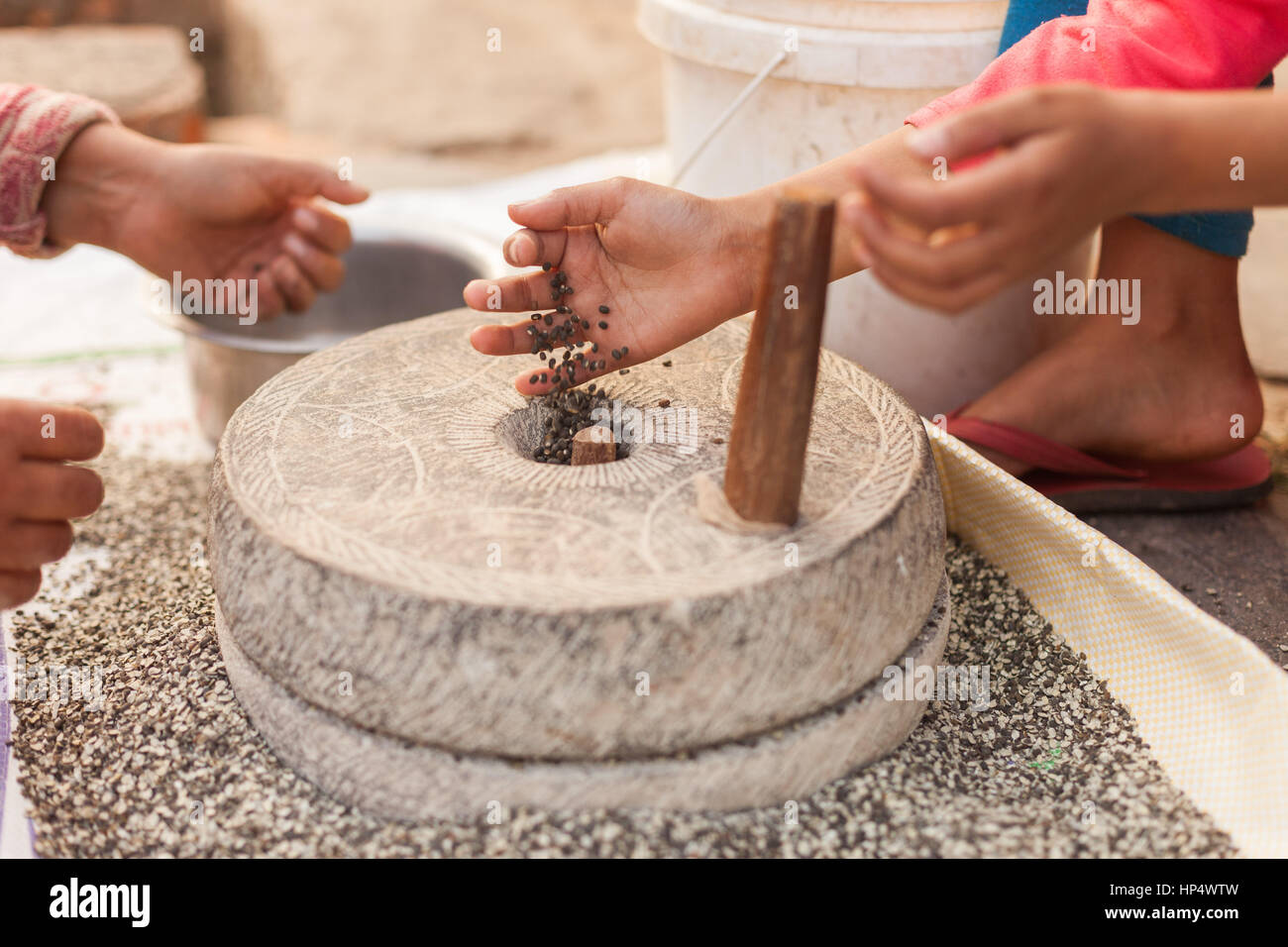 Newari woman grinding dal (dried, split pulses) with a hand-operated ...