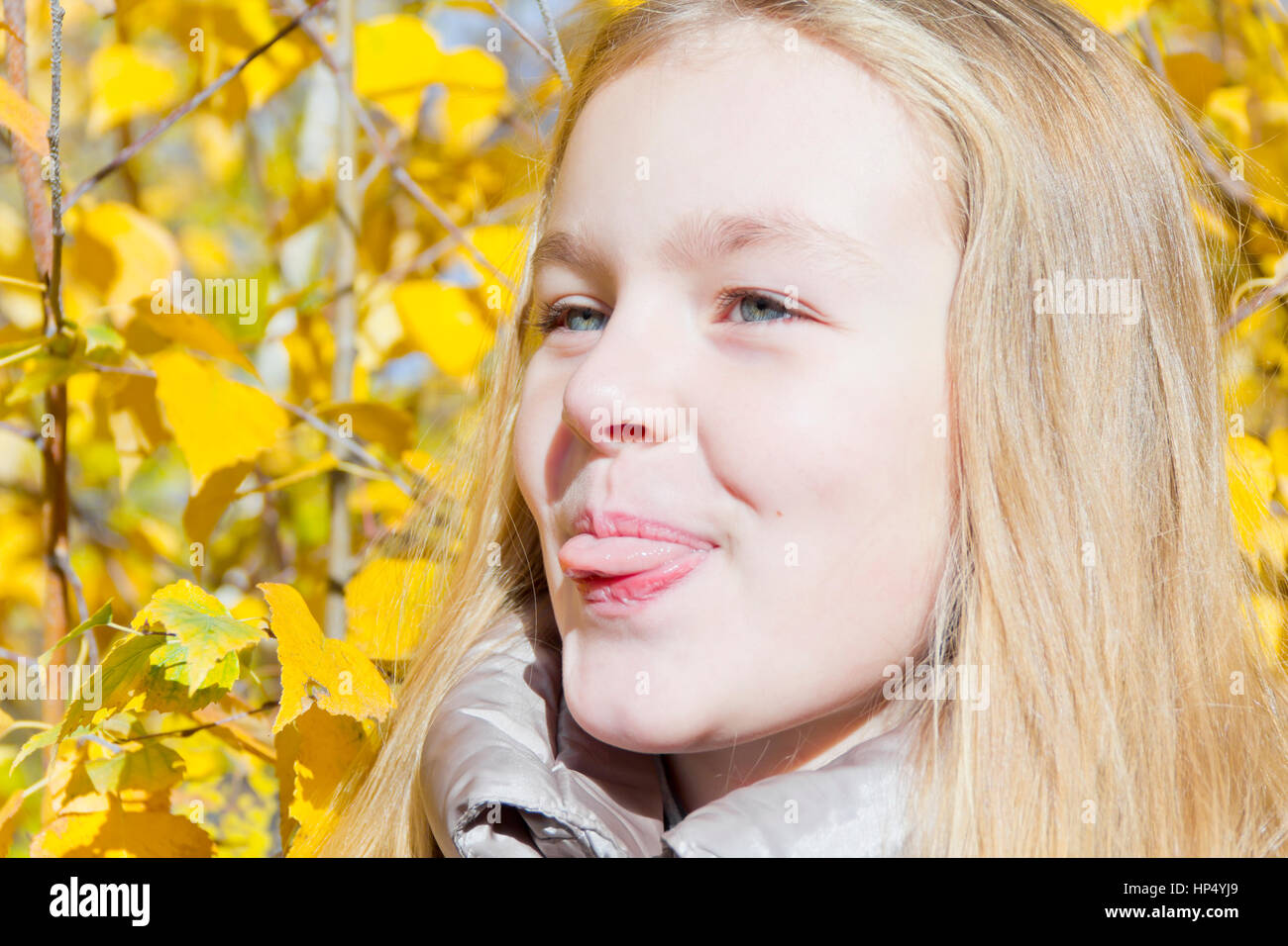 Autumn portrait of blond girl in sunlight put out tongue Stock Photo ...