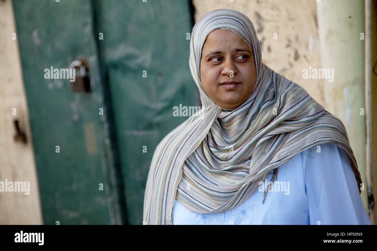 Port Louis, street scene, young woman, veiled, in front of green door ...