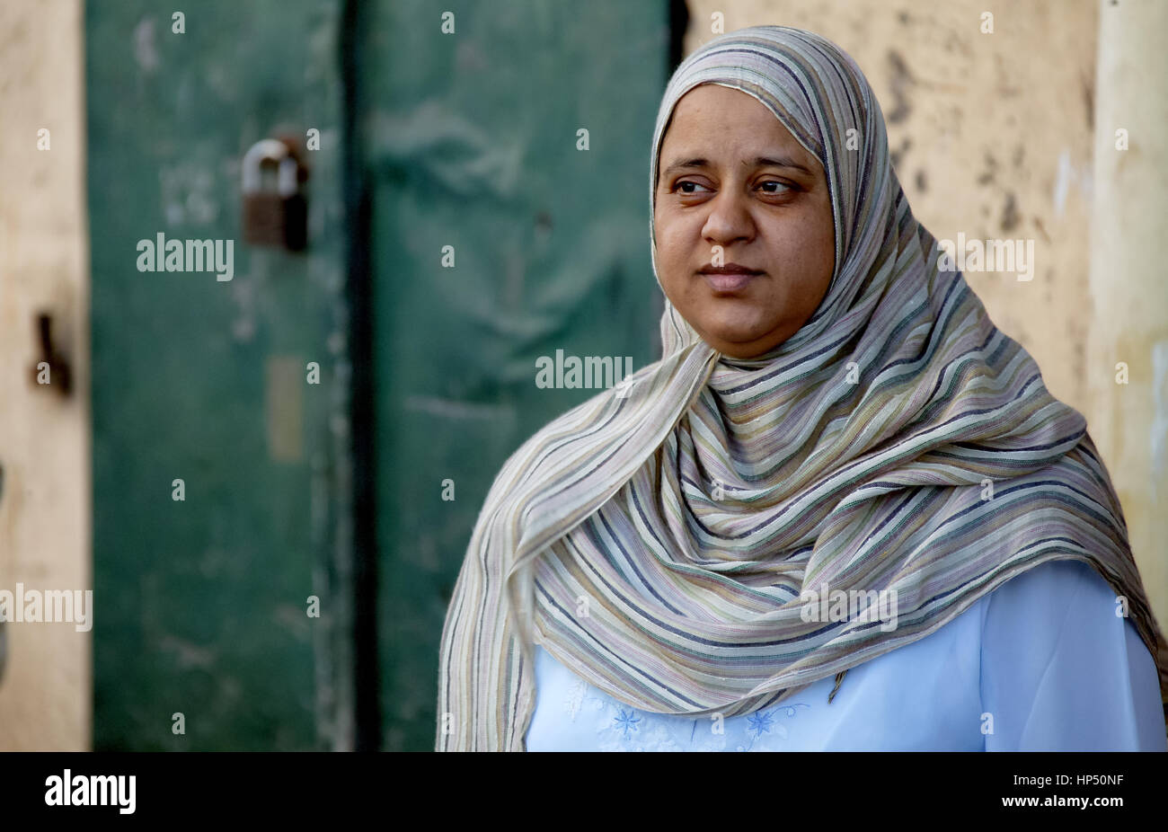 Port Louis, street scene, young woman, veiled, in front of green door ...