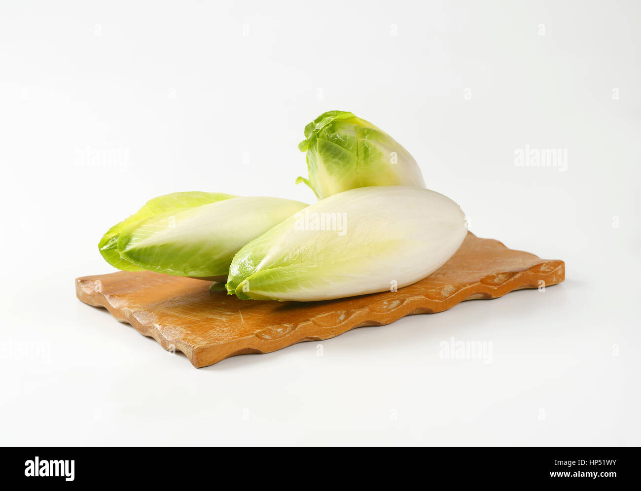 heads of fresh belgian endive on wooden cutting board Stock Photo - Alamy
