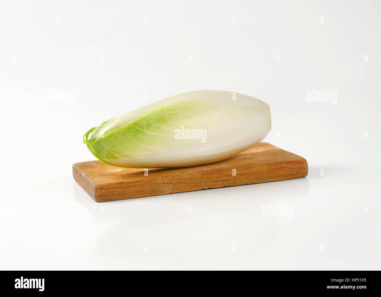 head of fresh belgian endive on wooden cutting board Stock Photo - Alamy