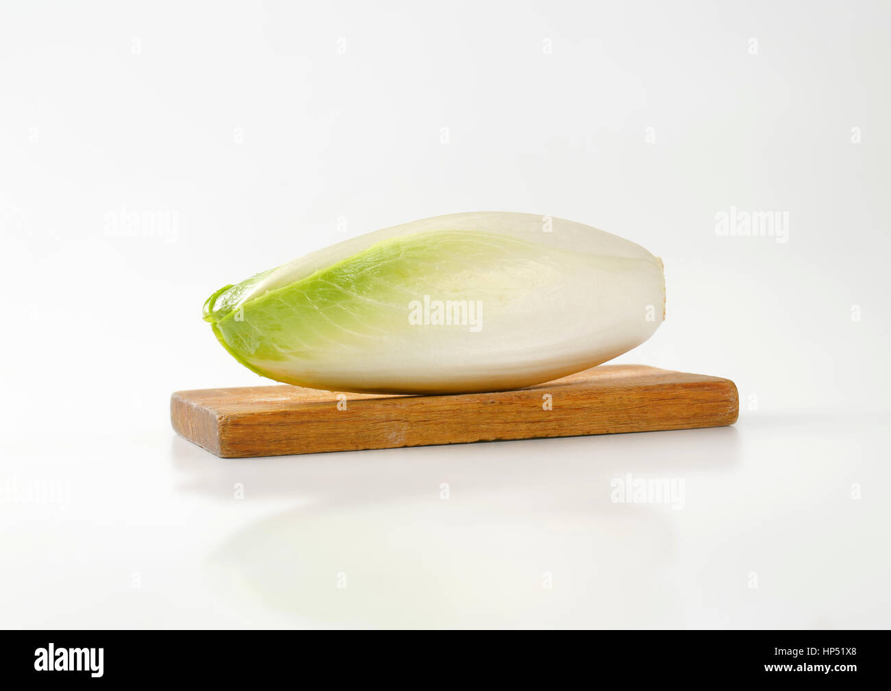 head of fresh belgian endive on wooden cutting board Stock Photo - Alamy