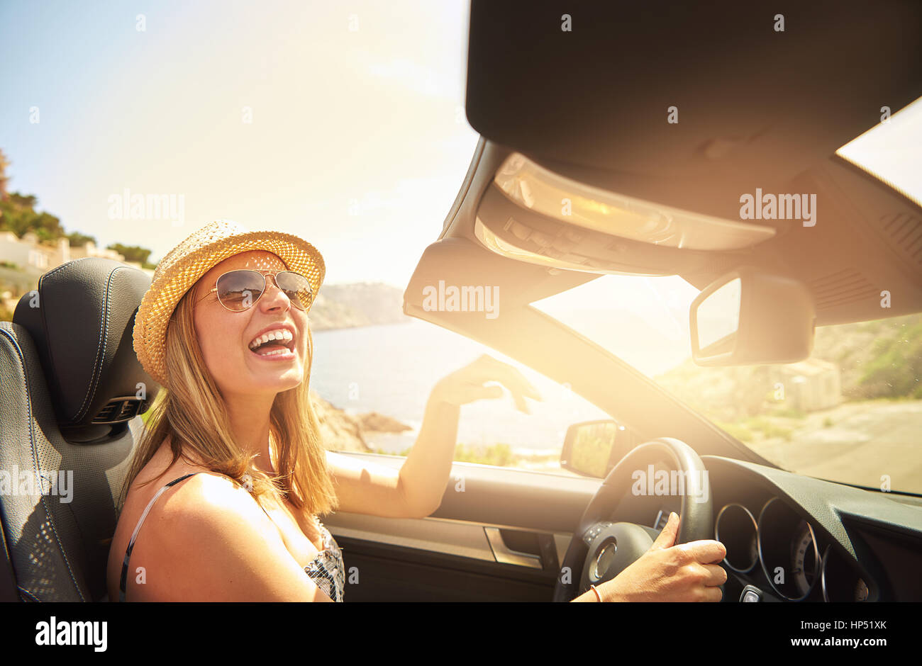 Single laughing young woman with hat and sunglasses driving her ...