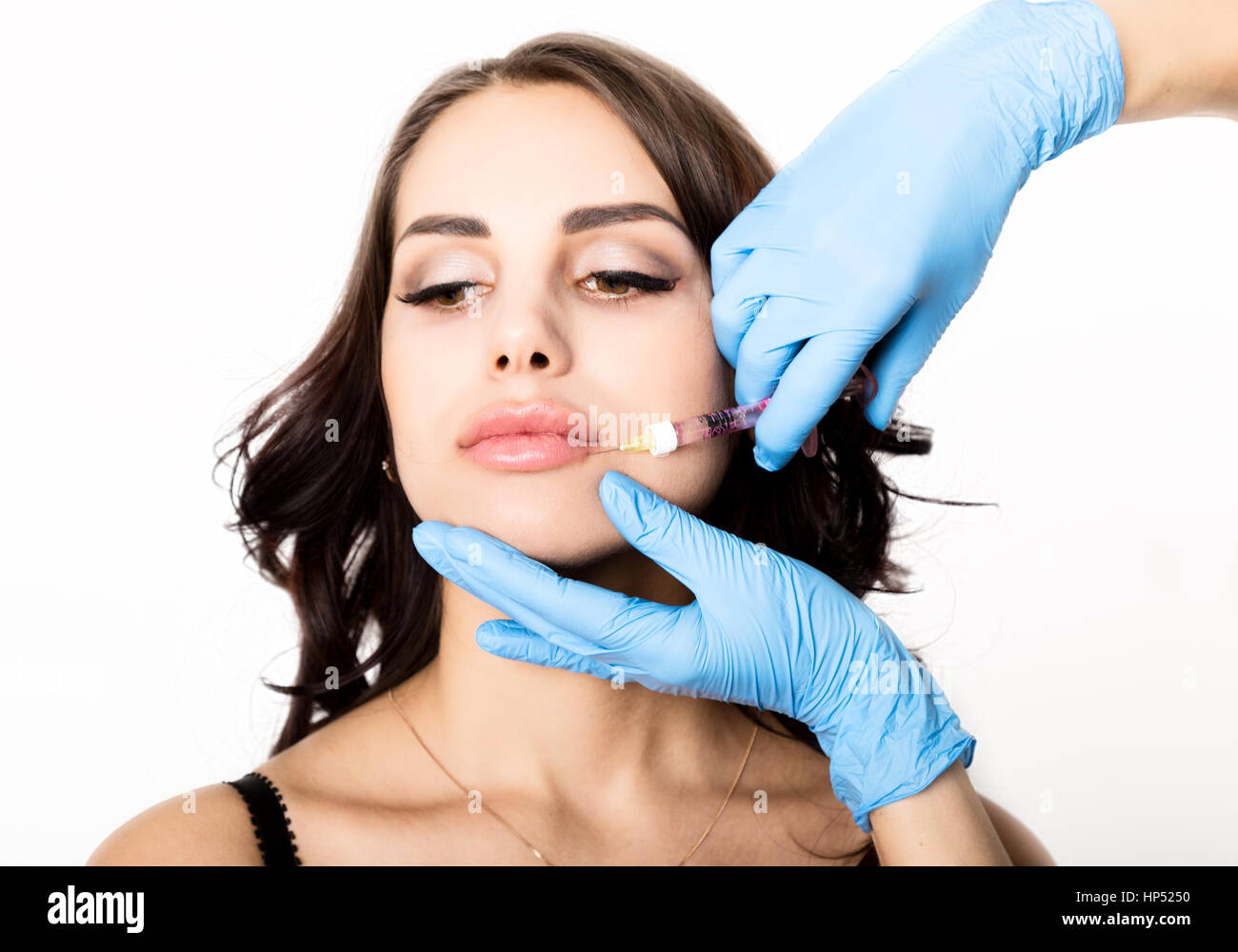 young woman gets beauty injection in eye and lips area from beautician ...