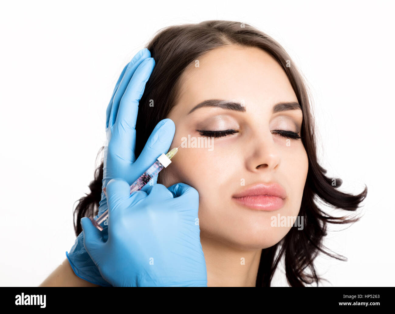 young woman gets beauty injection in eye and lips area from beautician ...