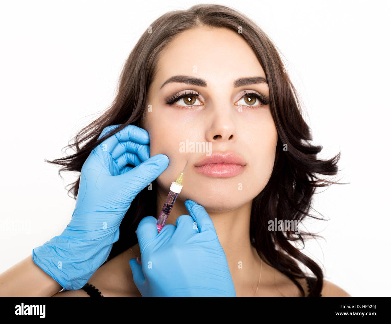young woman gets beauty injection in eye and lips area from beautician ...