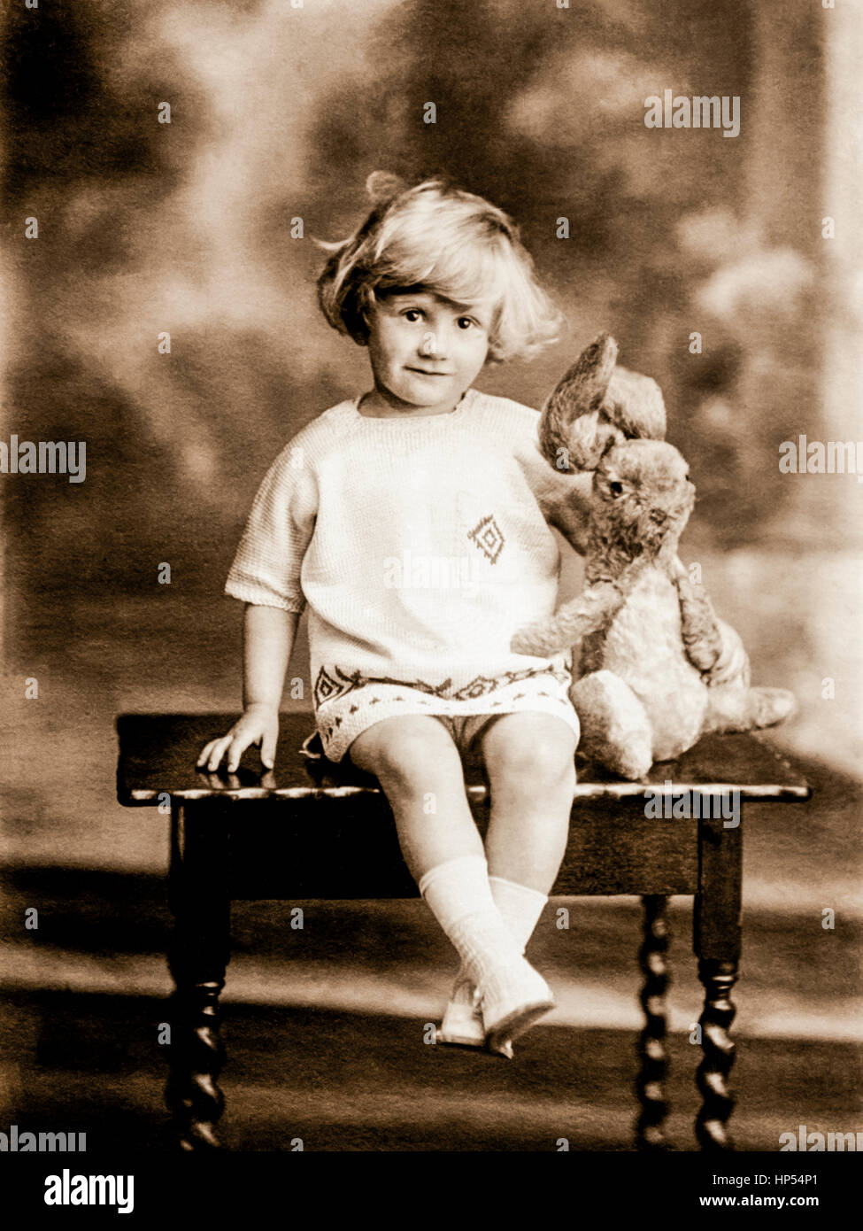 Formal Edwardian portrait of a small child sitting on a low table ...
