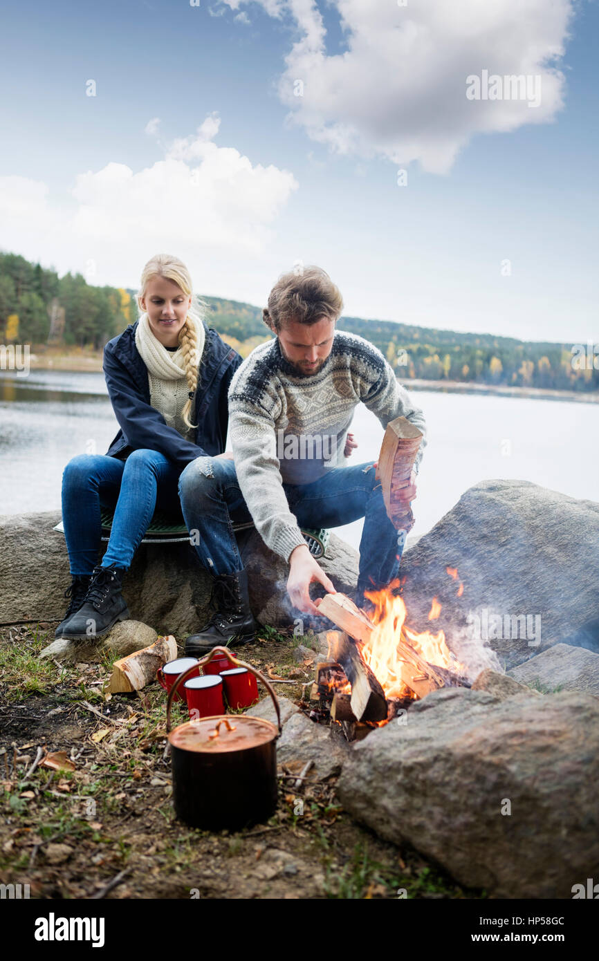 Hiking Couple Preparing Bonfire On Lakeshore Stock Photo - Alamy