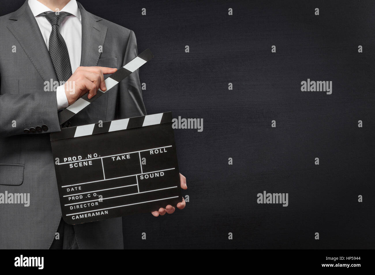 Man holding movie clapper board on chalkboard background with copyspace ...