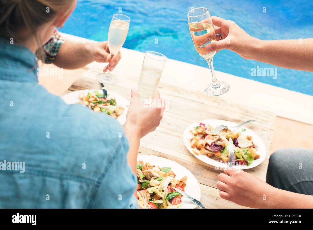 Young people sitting by the pool having dinner with champagne Stock ...