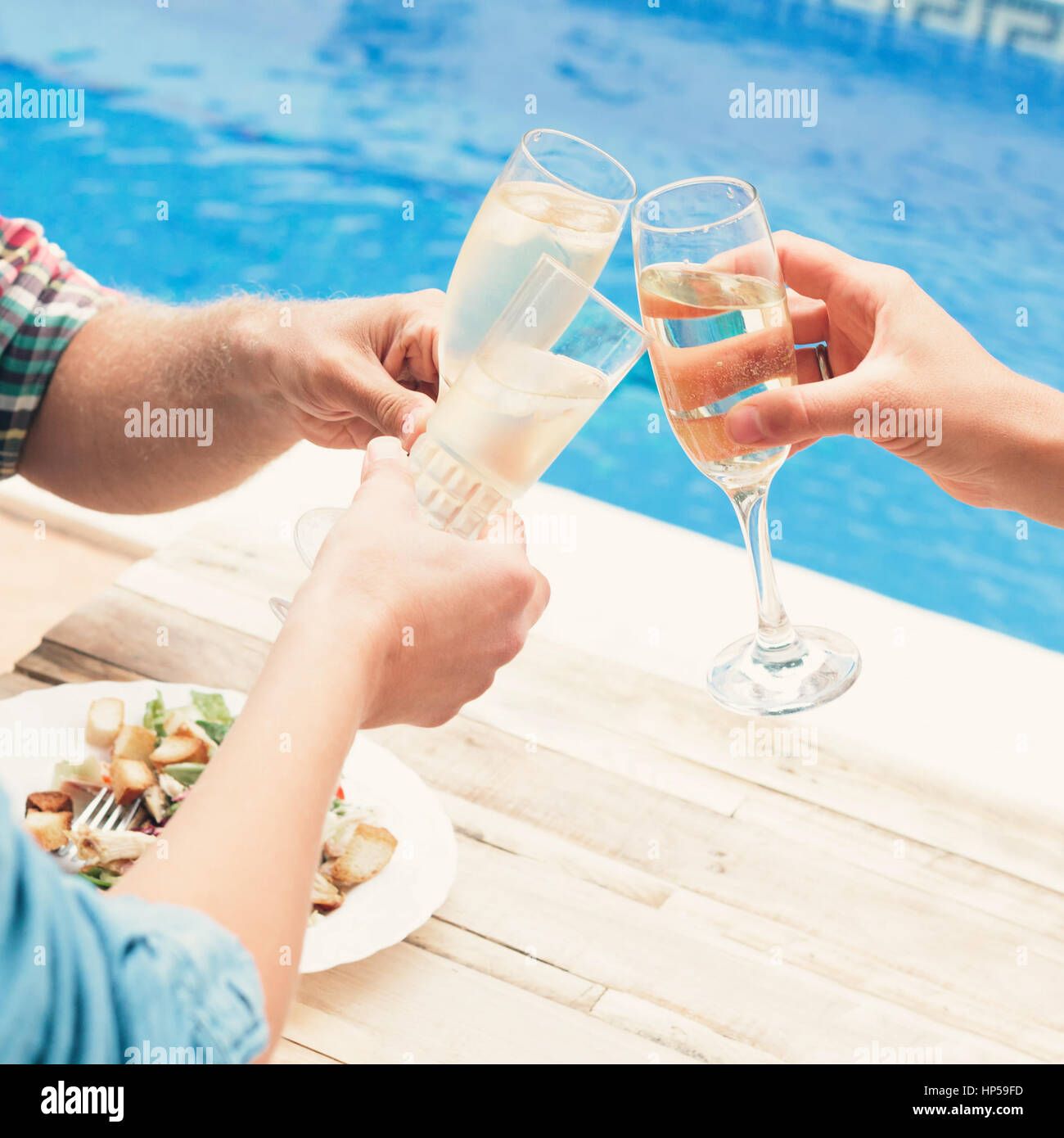 Closeup of friends toasting champagne having a dinner by a poolside ...