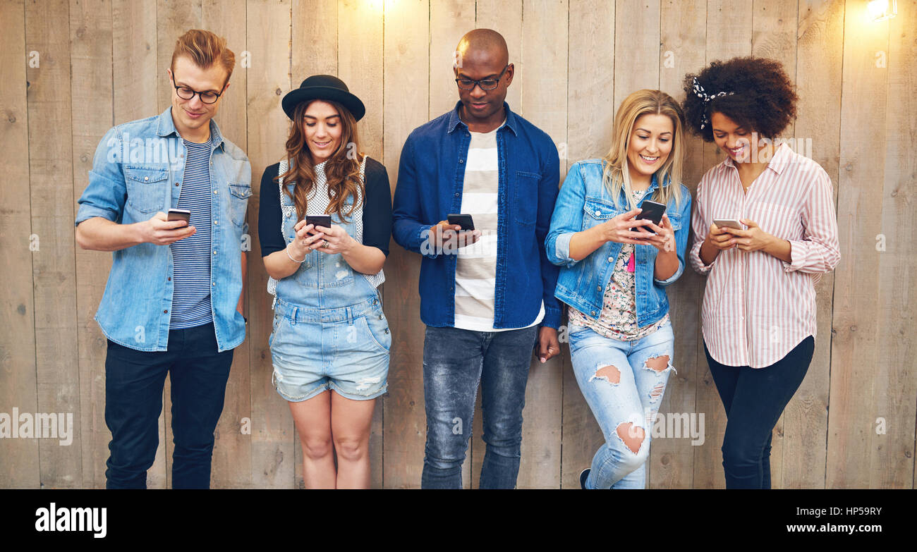 Group of young good looking people standing together over wooden wall ...