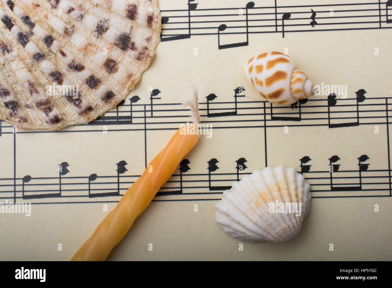 Seashells and a candle placed on a Musical notes Stock Photo - Alamy