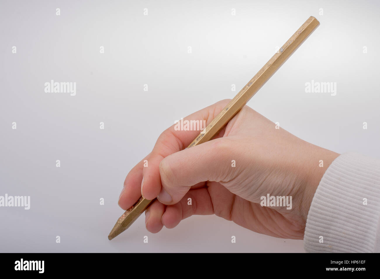 Hand holding a gold color pencil on a white background Stock Photo - Alamy
