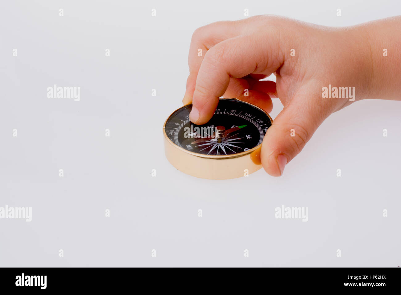 Child hand holding a compass on a white background Stock Photo - Alamy