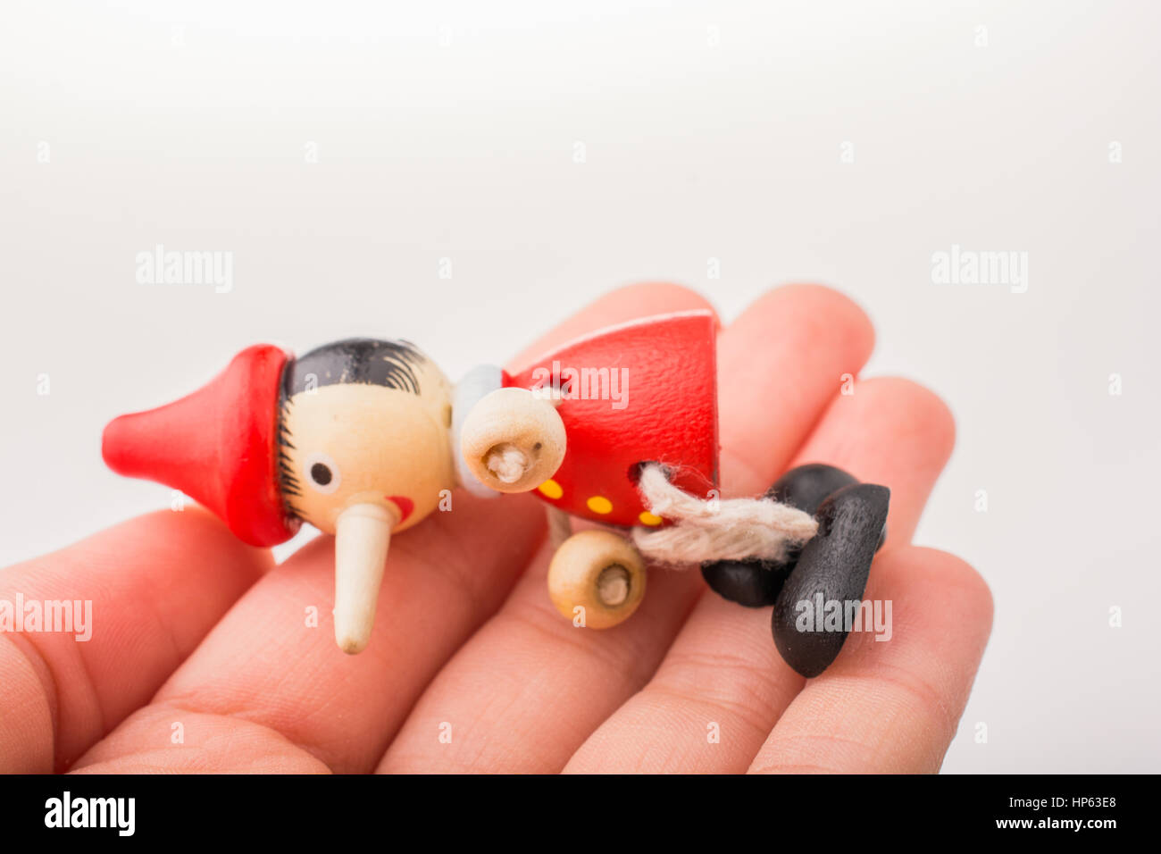 Wooden pinocchio doll in hand on a white background Stock Photo - Alamy