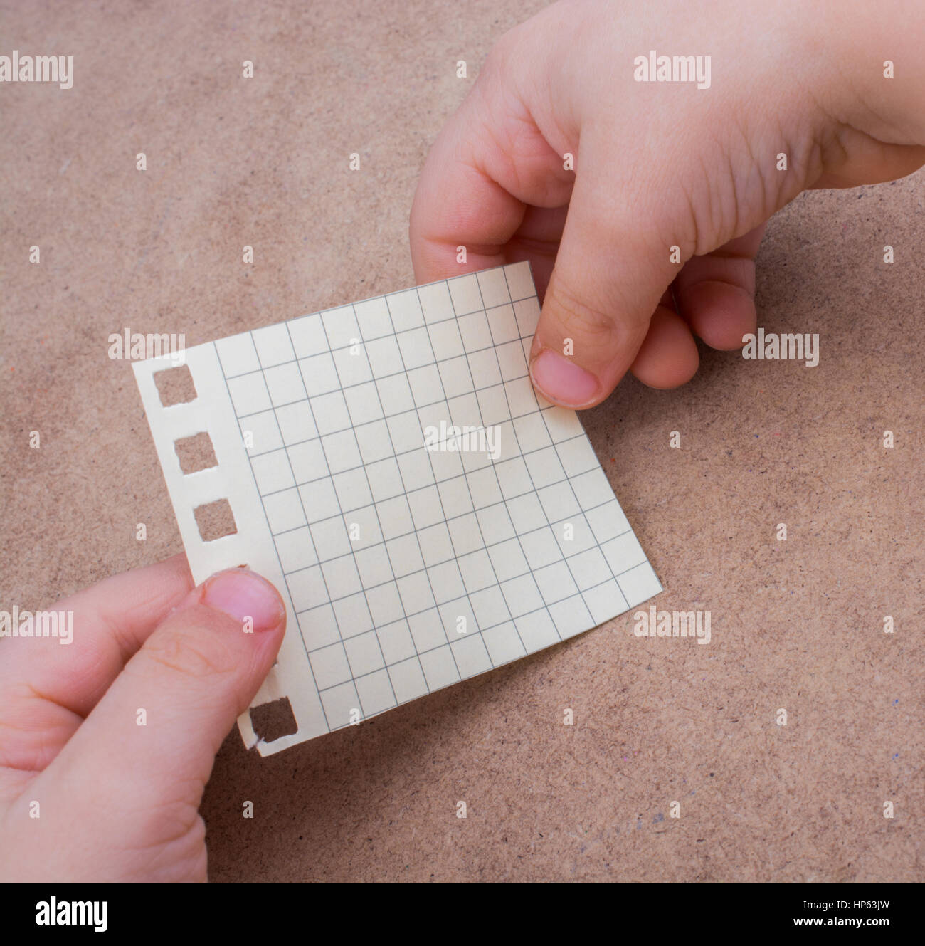 Hand holding a note paper on a brown background Stock Photo - Alamy