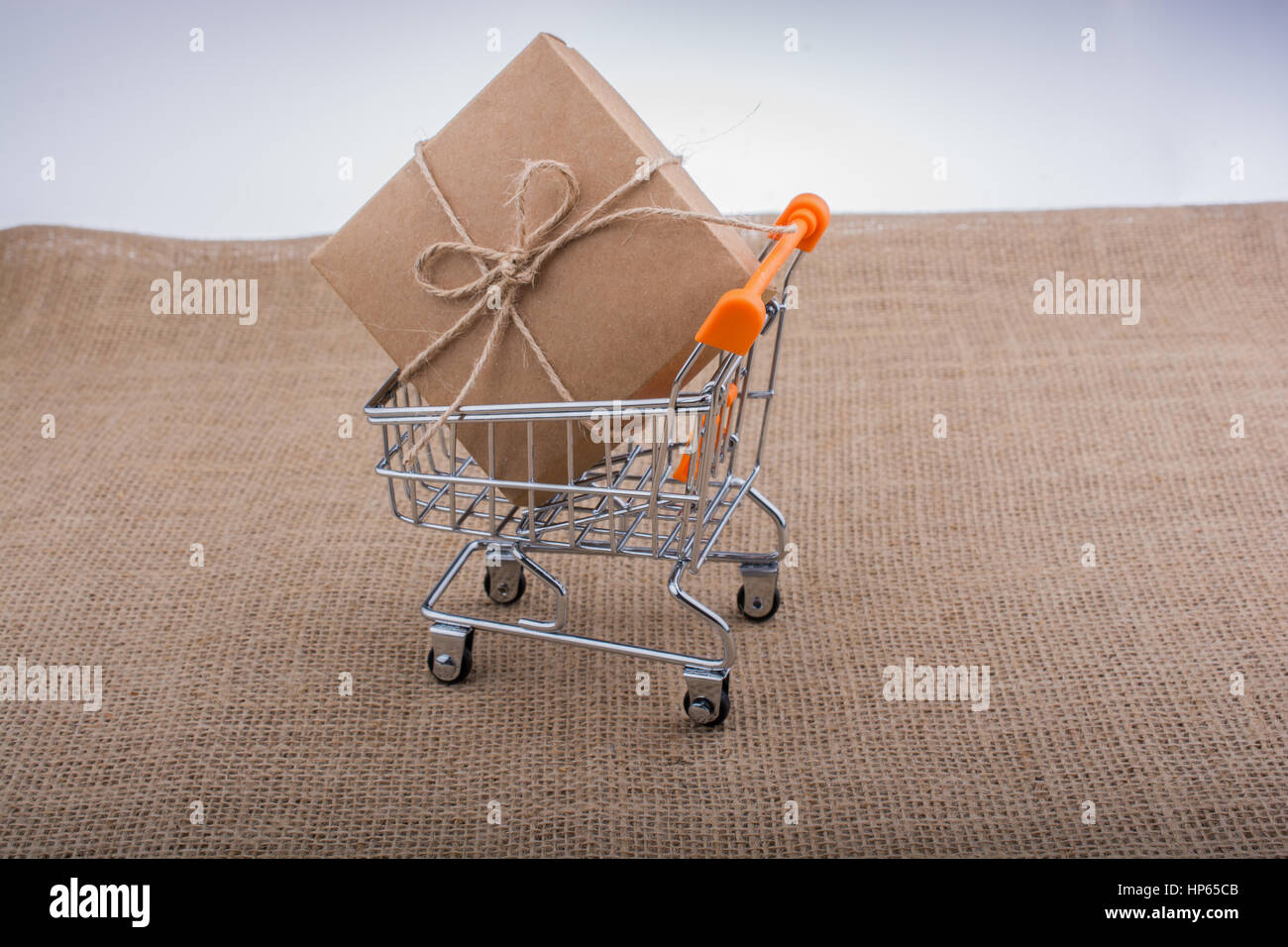 Gift box in shopping cart on a canvas background Stock Photo - Alamy
