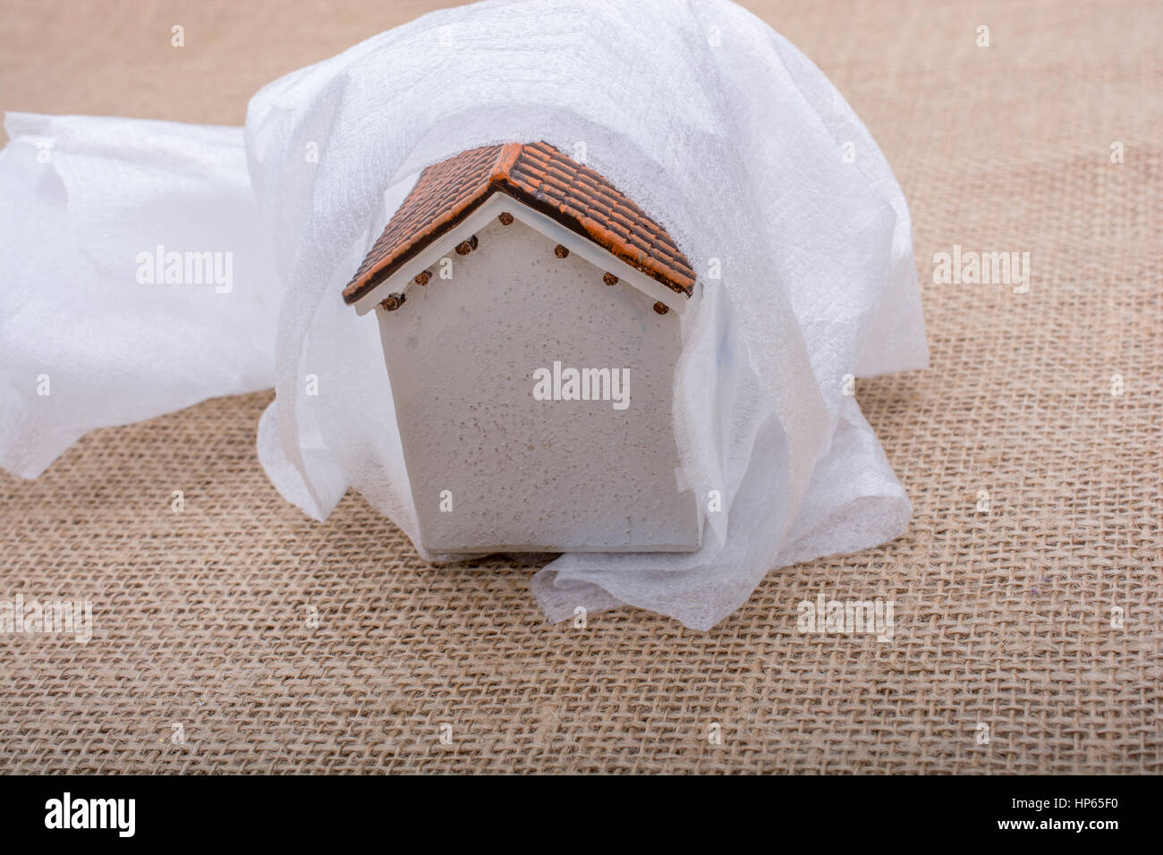 Little model house wrapped in paper on a brown background Stock Photo ...