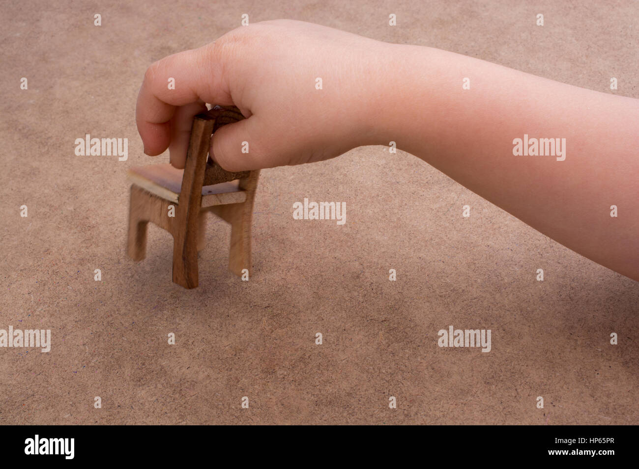 Child holding a wooden toy chair on brown background Stock Photo - Alamy