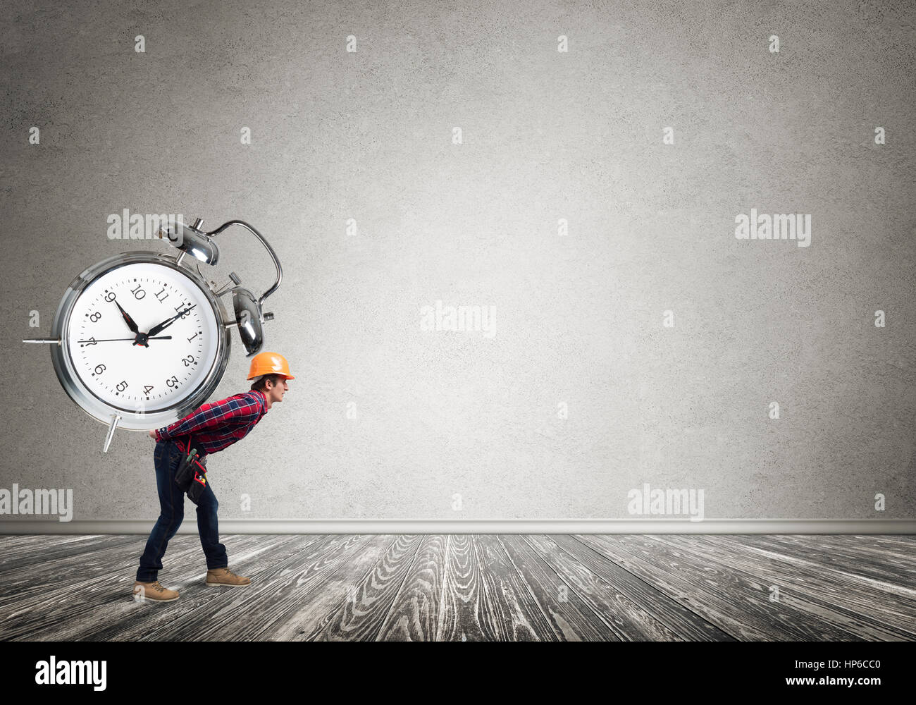 Builder man in helmet carrying alarm clock on back Stock Photo - Alamy