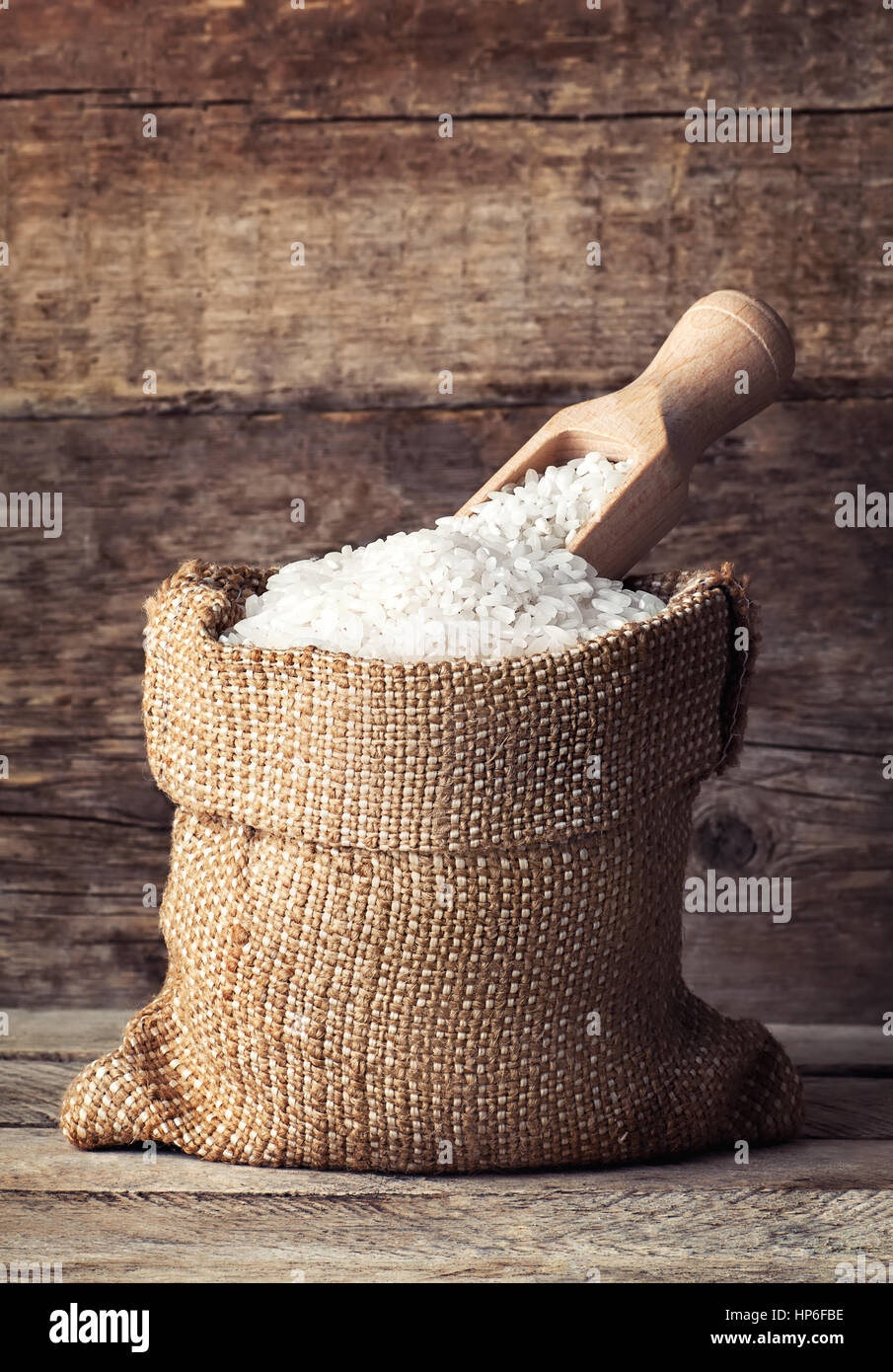 raw white rice in burlap bag with scoop on wooden background. Full sack ...