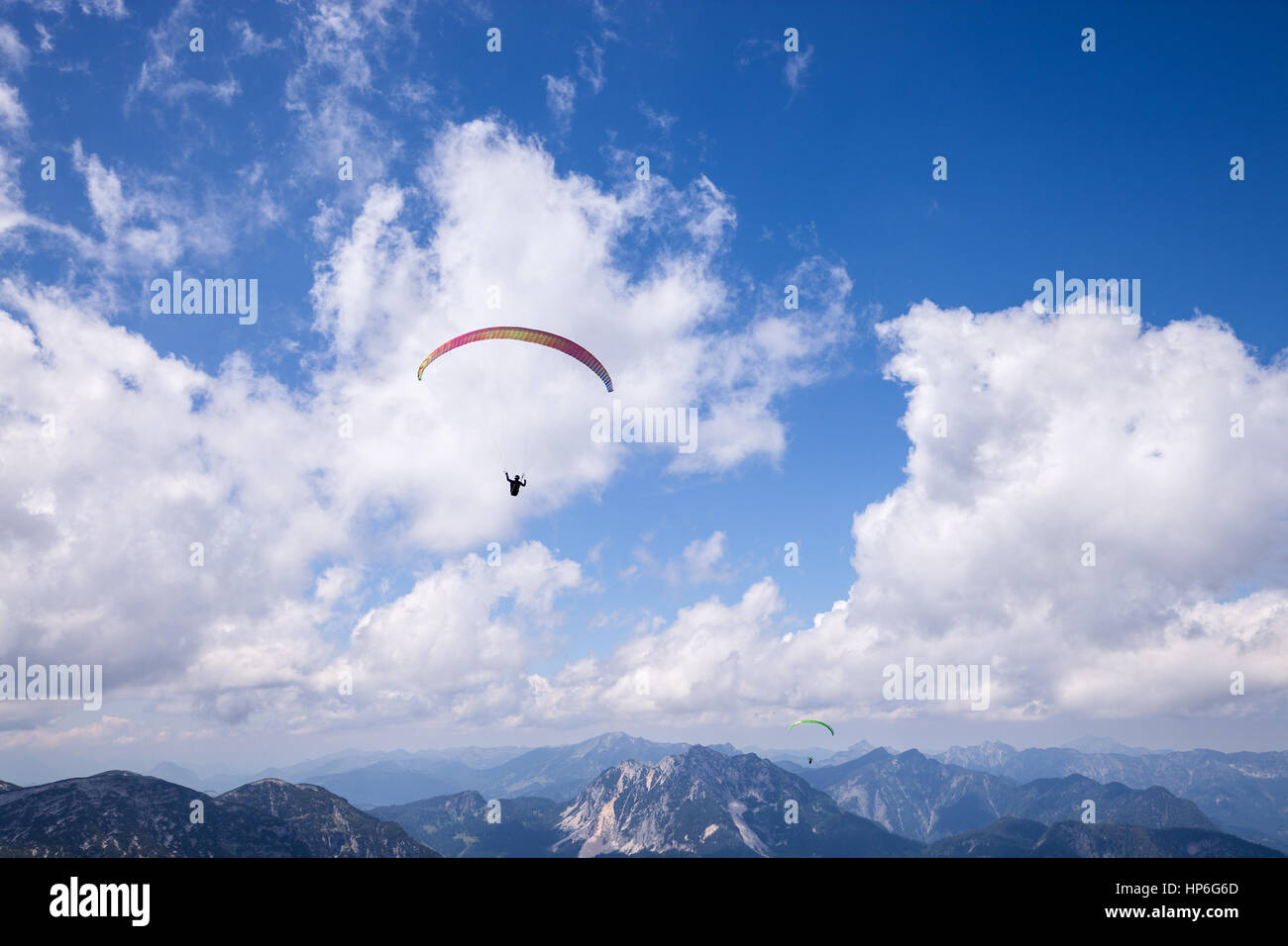 Parachute jumping extreme sport. Paraglider flying over mountains in ...