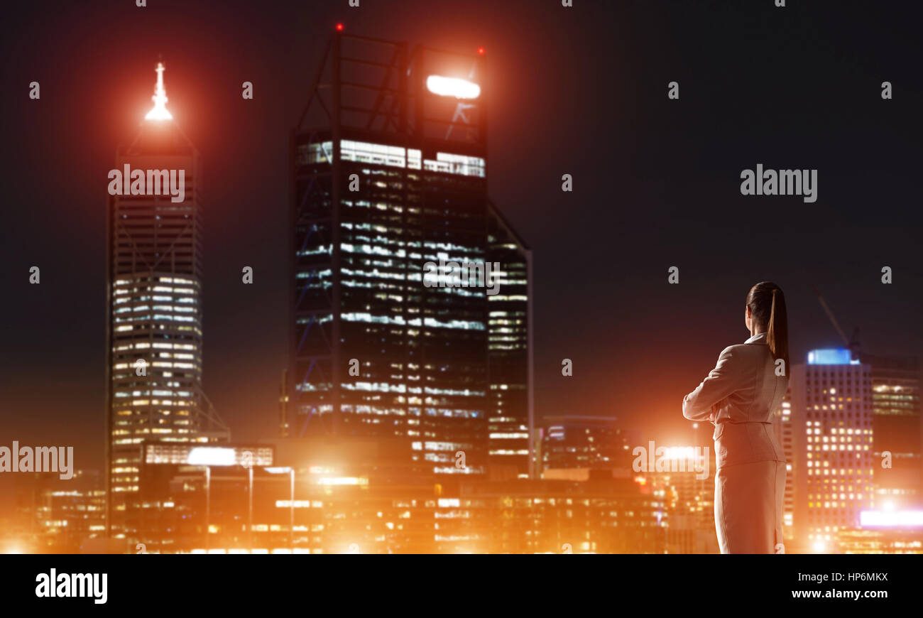 Rear view of elegant businesswoman viewing lights of night city Stock ...