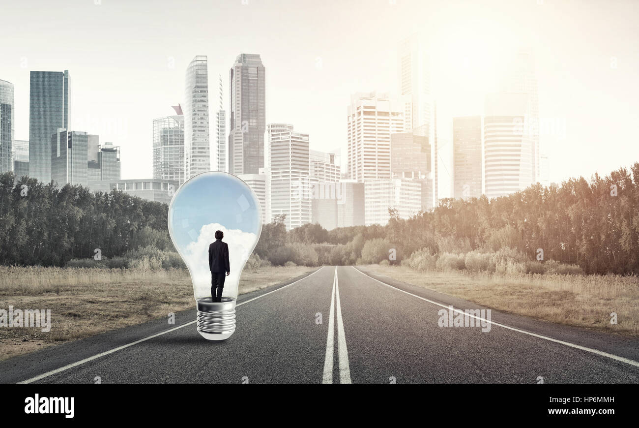 Young businessman trapped inside of light bulb on asphalt road Stock ...
