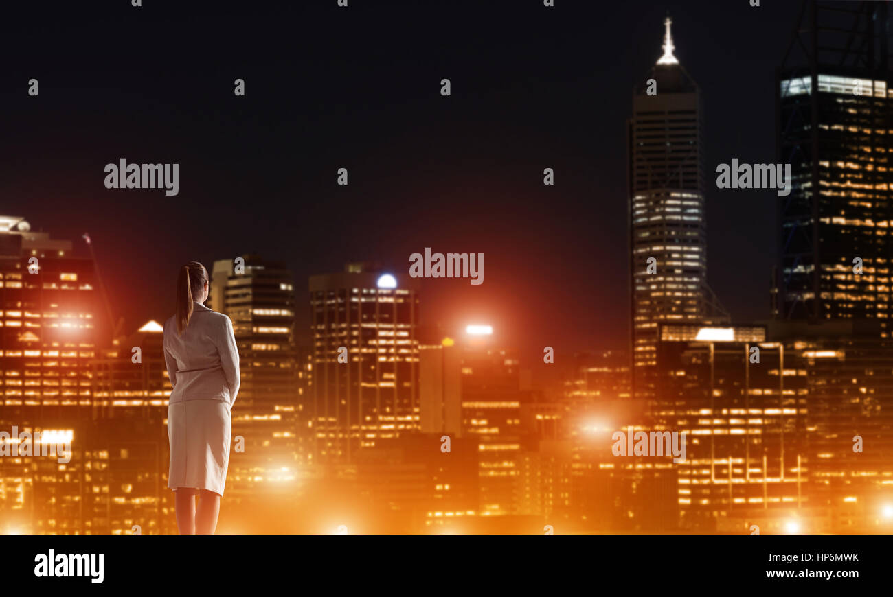 Rear view of elegant businesswoman viewing lights of night city Stock ...