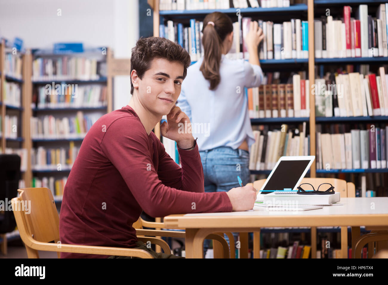 Young student studying at the library, girl and bookshelves on ...