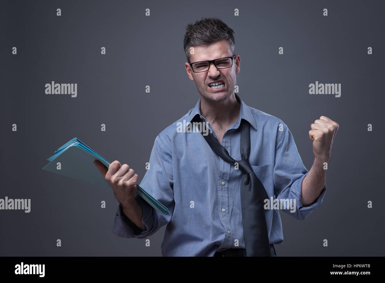 Angry untidy businessman with files snarling with fist raised Stock ...