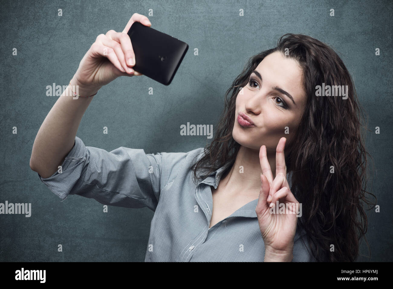 Cheerful girl taking a selfie with her mobile touch screen smartphone ...