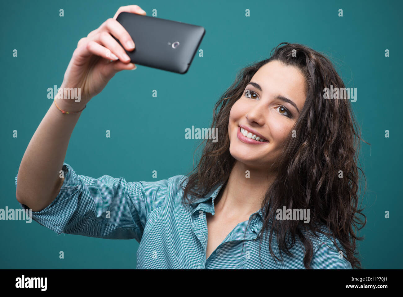 Cheerful girl taking a selfie with her mobile touch screen smartphone ...