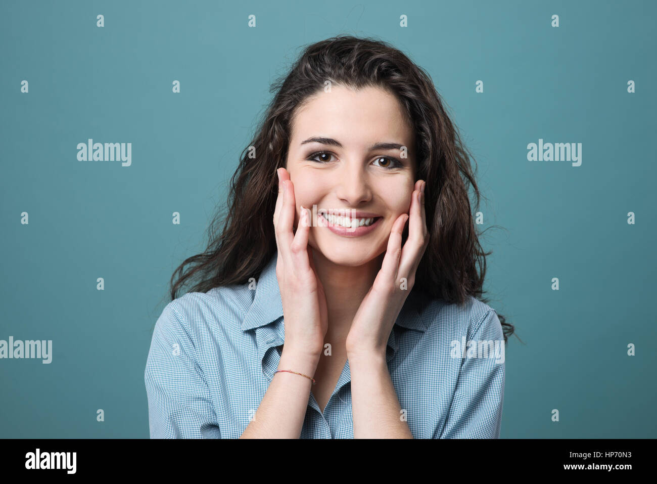 Cheerful young woman smiling and touching her cheeks, freshness and ...