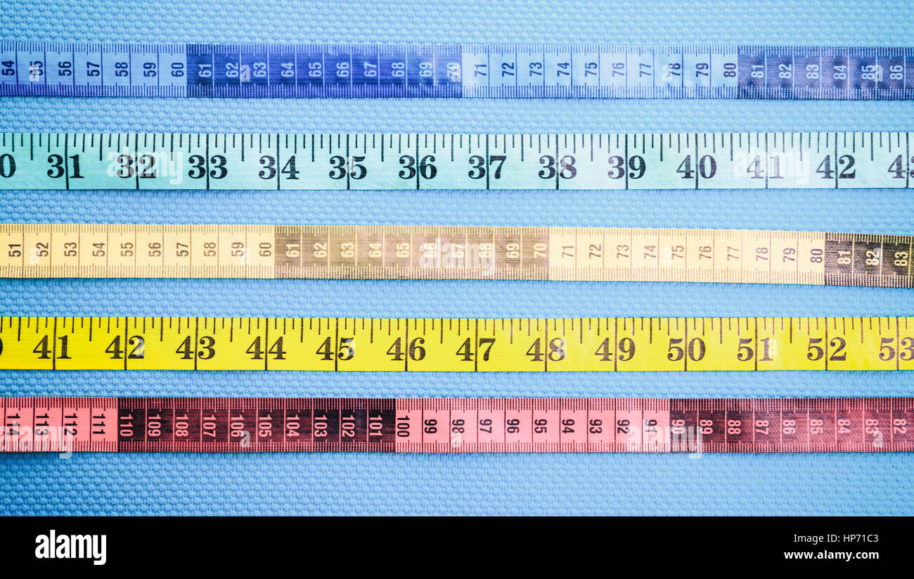 Set of colorful measure tapes on a blue background Stock Photo - Alamy