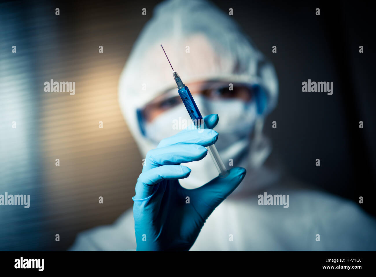 Researcher in hazmat protective suit preparing a syringe for injection ...